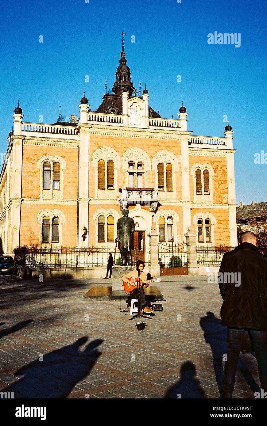 Girl playing guitar on the street in front of the Jovan Jovanović Zmaj ...