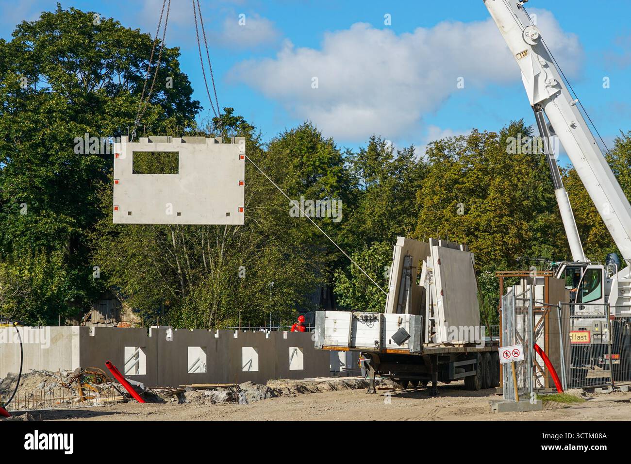 Large crane lifts precast concrete wall panel at multi-story ...
