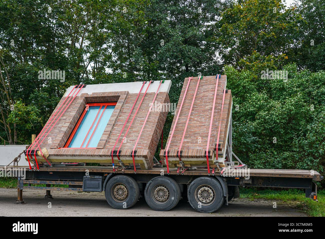 Flatbed truck transporting prefabricated brick wall panels with windows ...