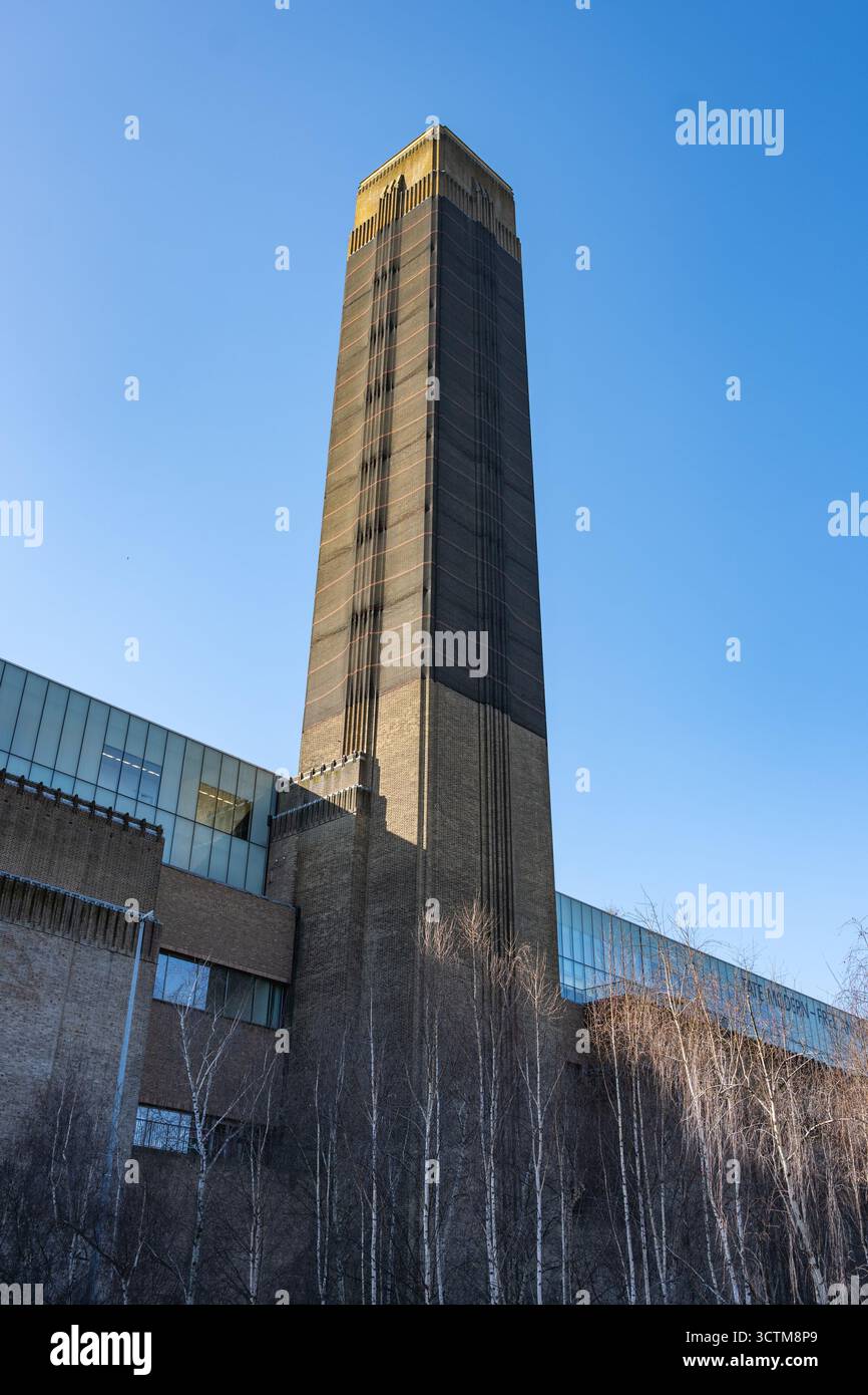 The towering chimney of Tate Modern stands against a clear blue sky in ...