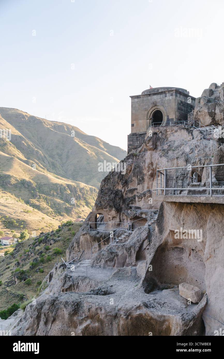 View of ancient cave monastery carved into a steep, rocky cliff face ...
