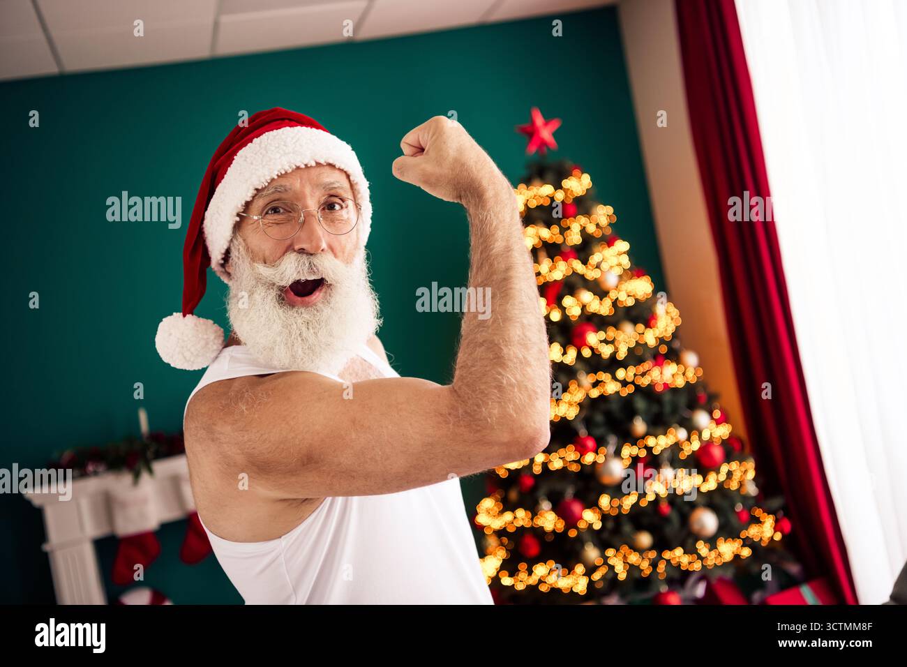 Festive senior Santa Claus flexing his arm with holiday spirit indoors ...