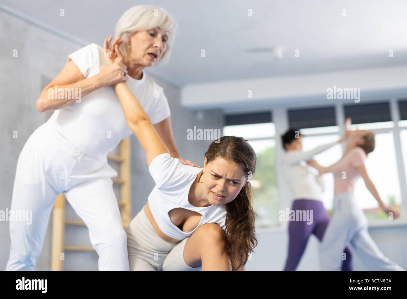 Mature woman applying arm lock technique in mock bout during self ...