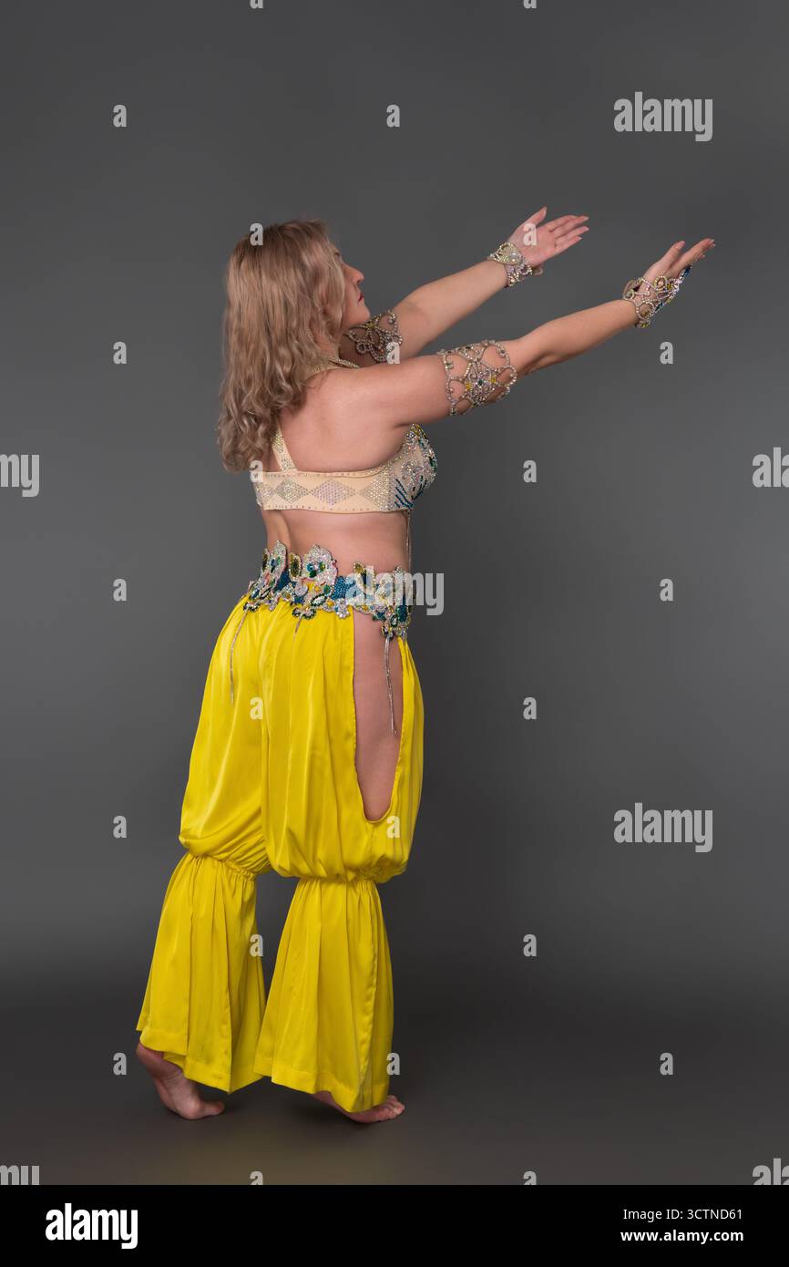 Three quarter rear view of curvy woman dancer with hand raised wearing ...