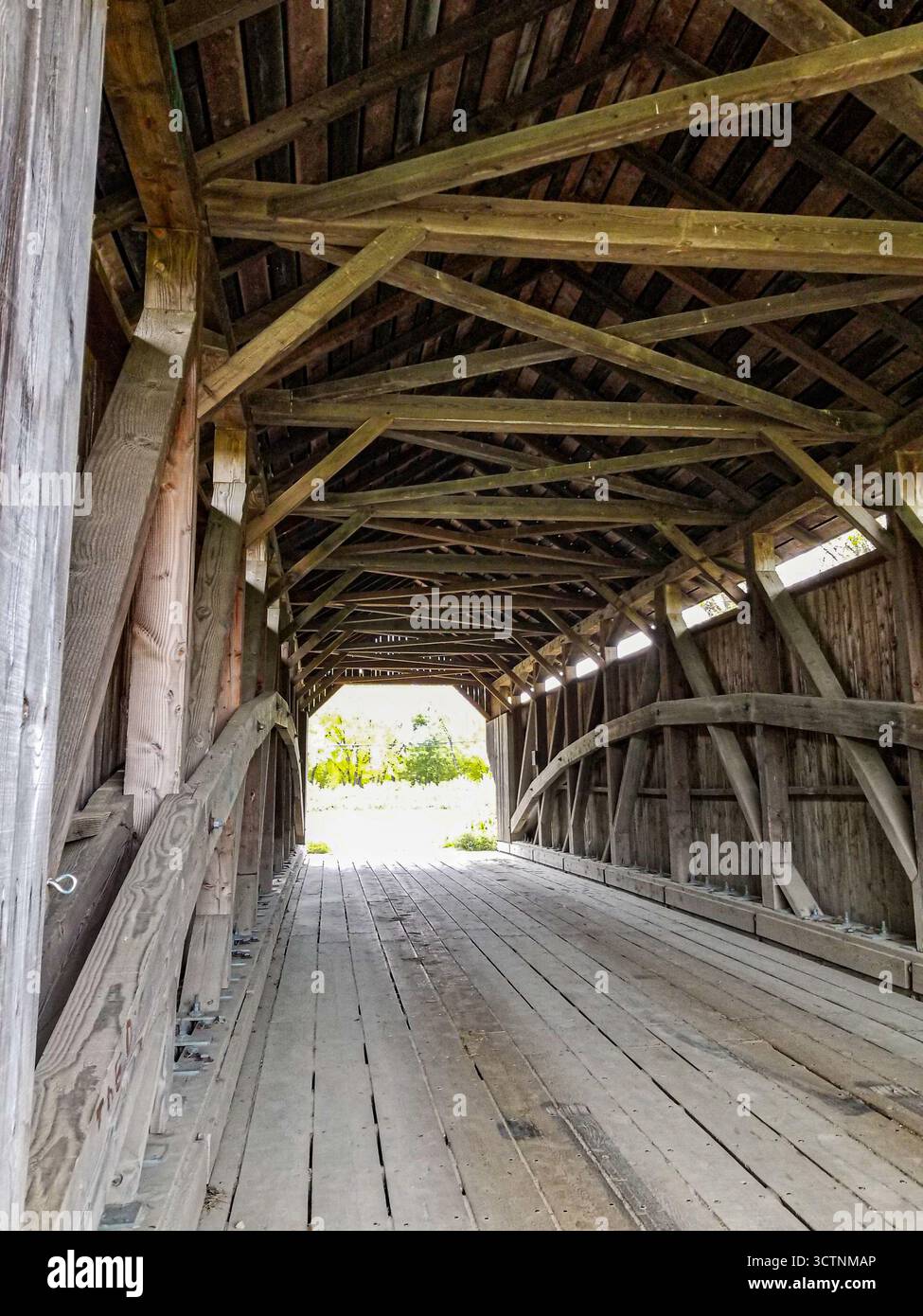 The interior of an old wooden covered bridge showing the wooden beams ...