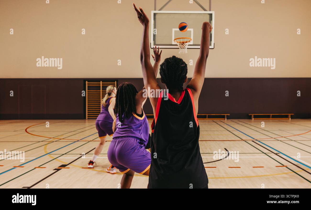 Three women participating in a basketball game, focusing on shooting ...