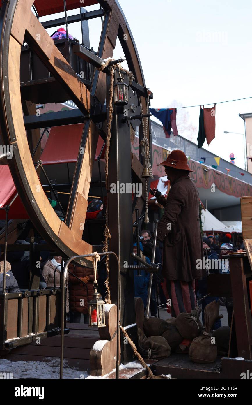 Vintage-style wooden Ferris wheel operated manually by a man in ...