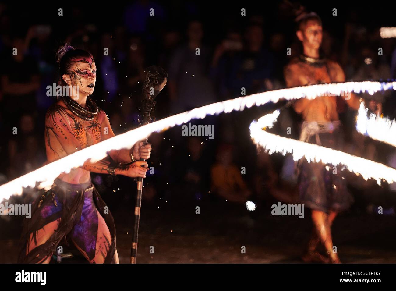 Female fire dancer creates circular flame patterns with spinning staff ...