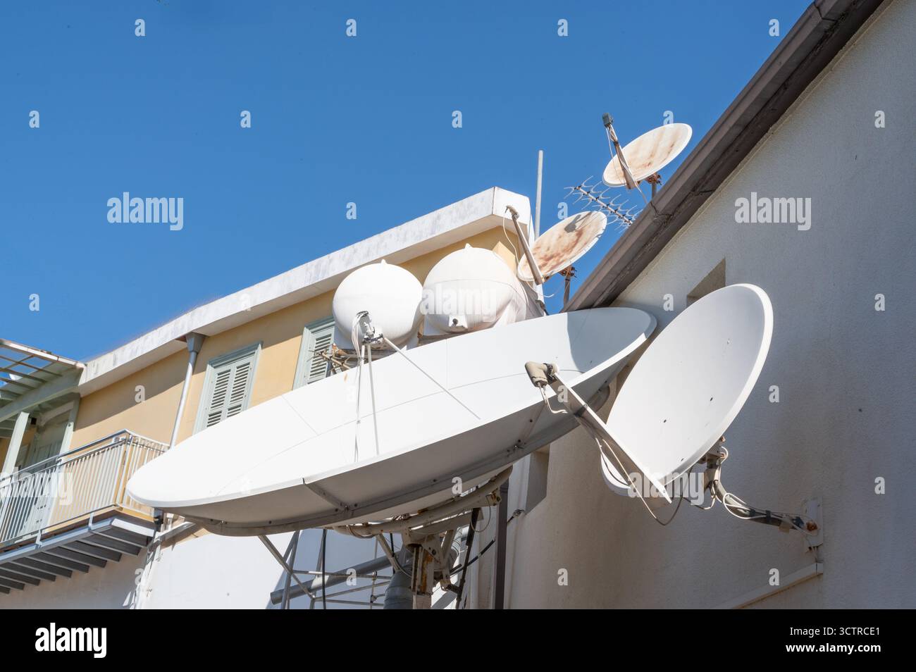 A cluster of satellite dishes installed on the side of a high building ...