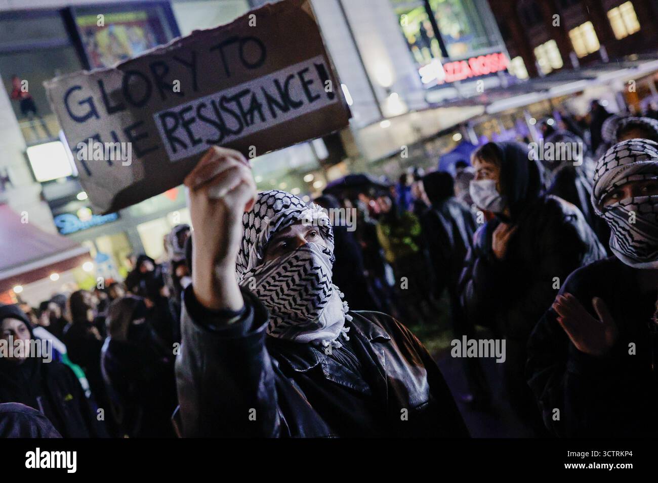A protester wrapped in a headscarf holds a placard saying "Glory to the ...