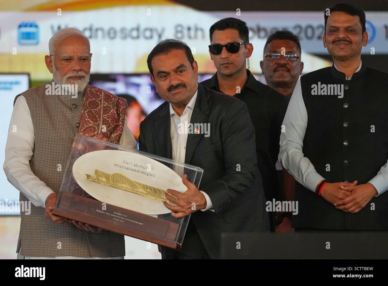 The Chairman of the Adani Group, Gautam Adani, second left, presents a ...