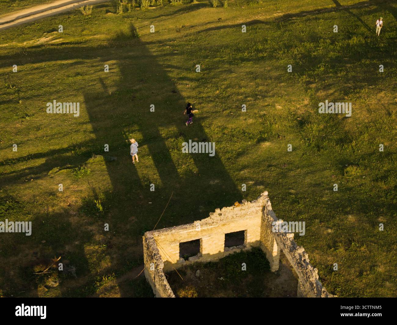 Aerial view of sun casts long shadows across the grassy expanse near a ...