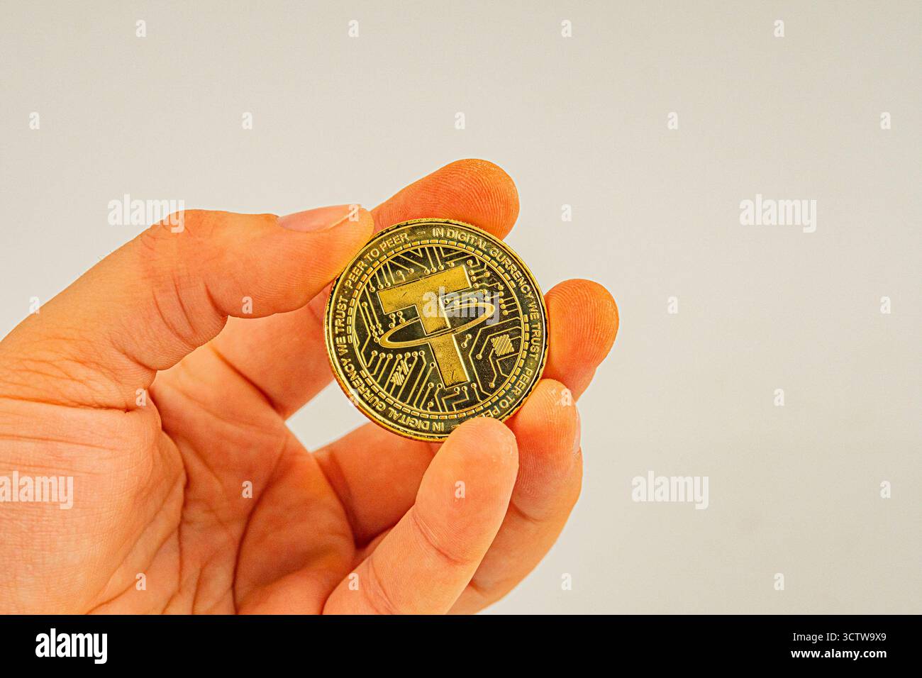 A hand holds a gold Tether coin token with the Bitcoin logo The token ...