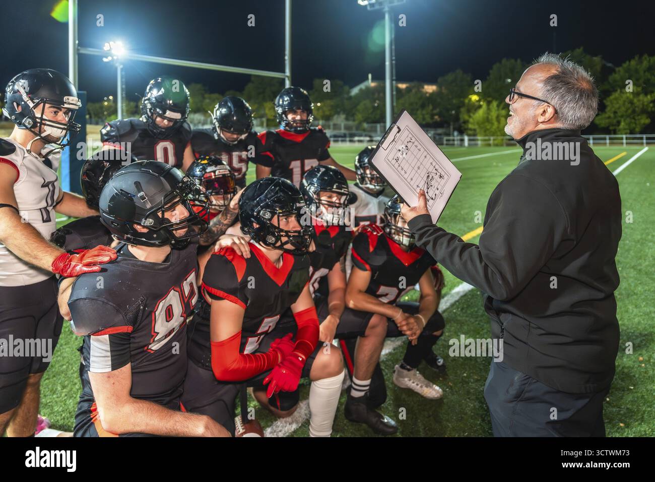 American football coach holds clipboard with play diagram, instructing ...