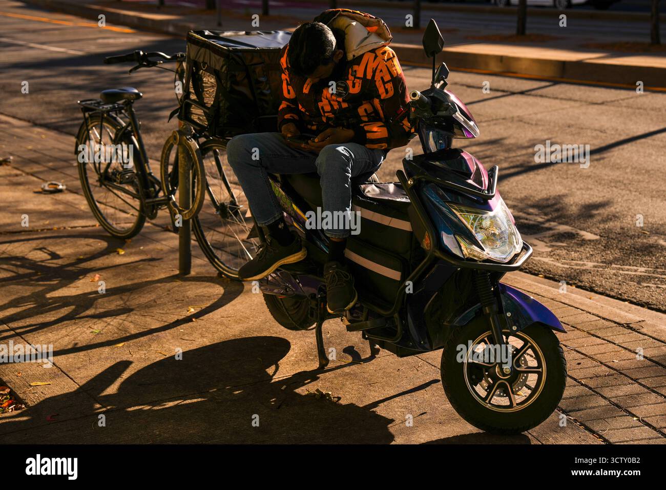 A food delivery courier waits for orders outside a restaurant in ...