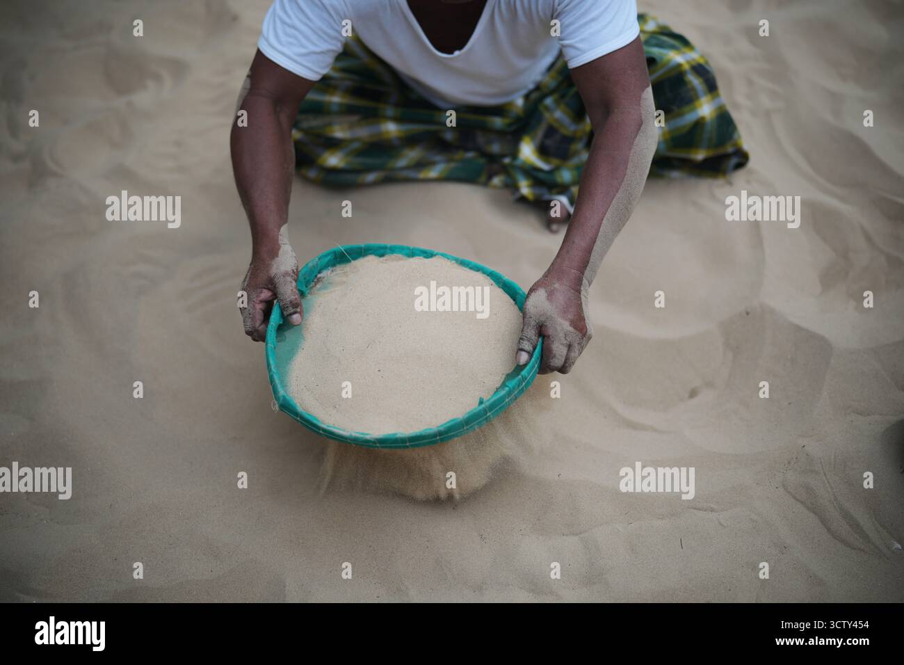 Adnan, only one name given, uses a sieve to clean sand in a sandpit in ...