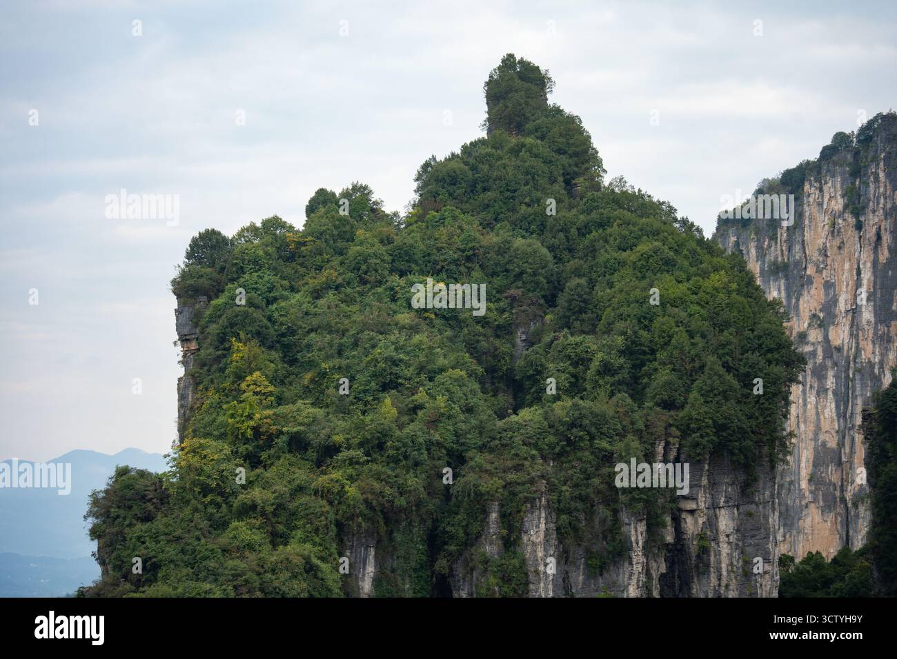 Green mountain peaks rise against a cloudy sky, showing steep cliffs ...