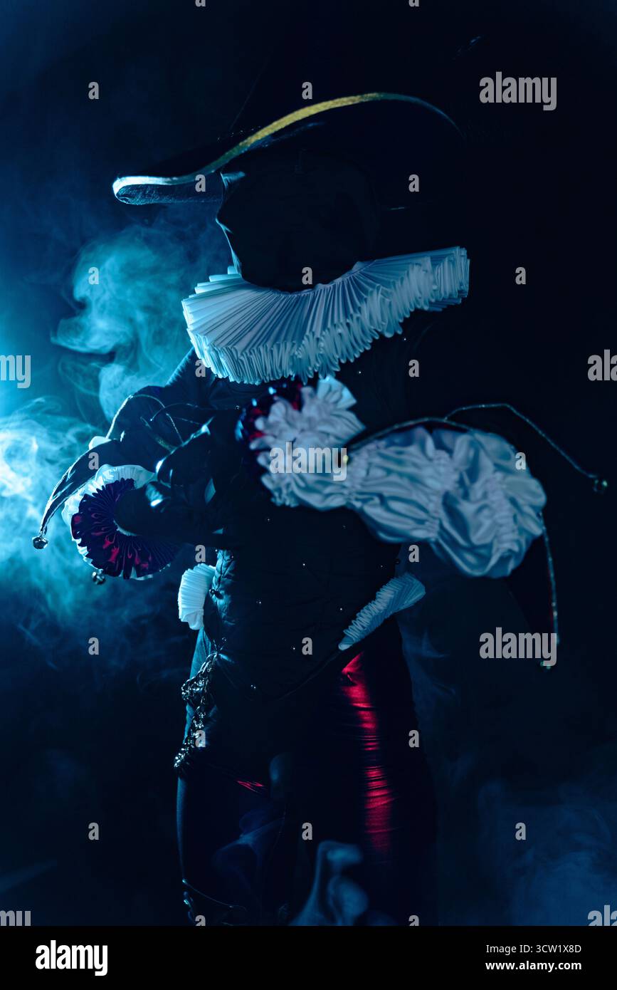 Dark and dramatic shot of mysterious jester character standing in dense ...
