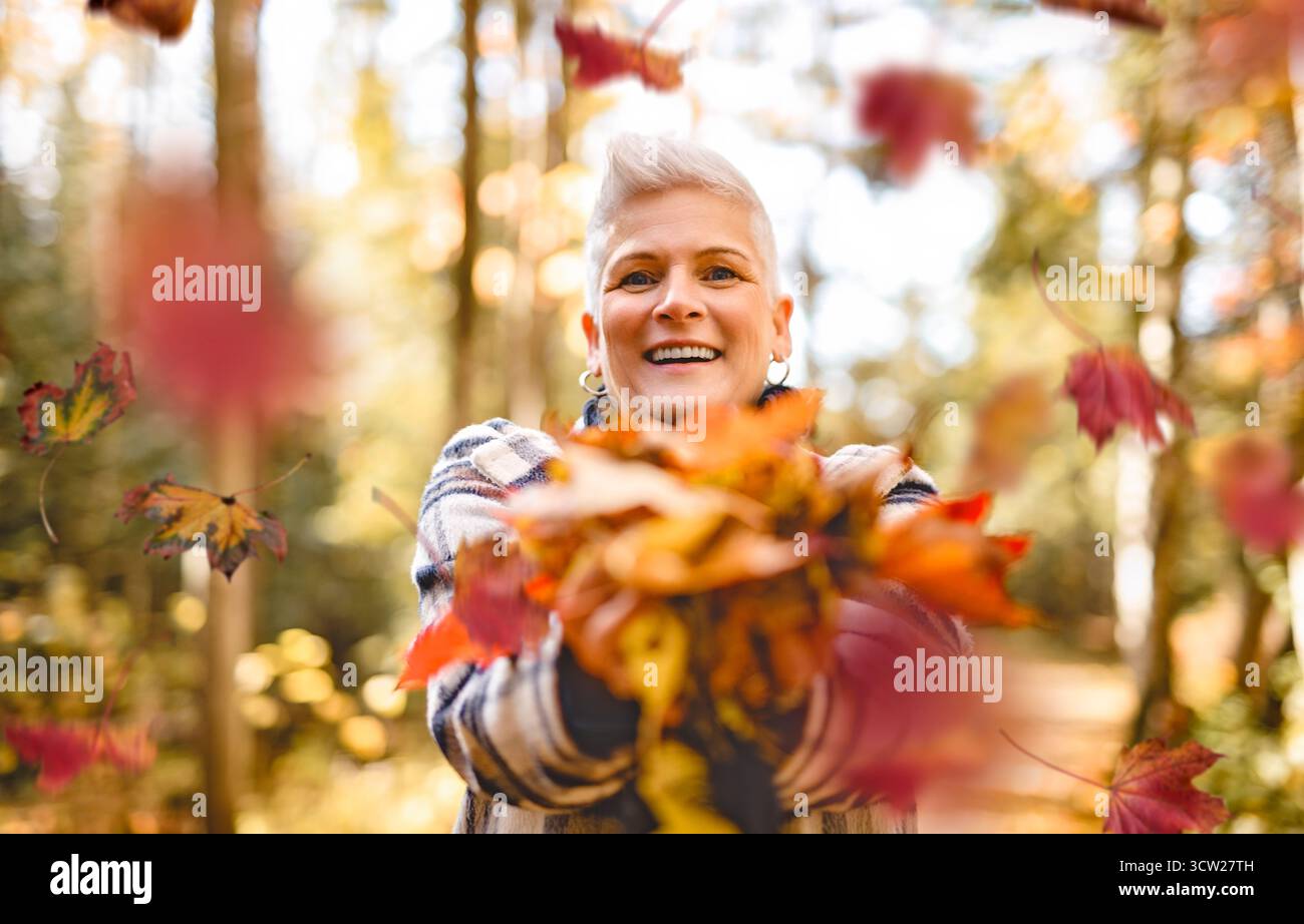 A Mature woman in autumn forest, dressed in cozy fall attire ...
