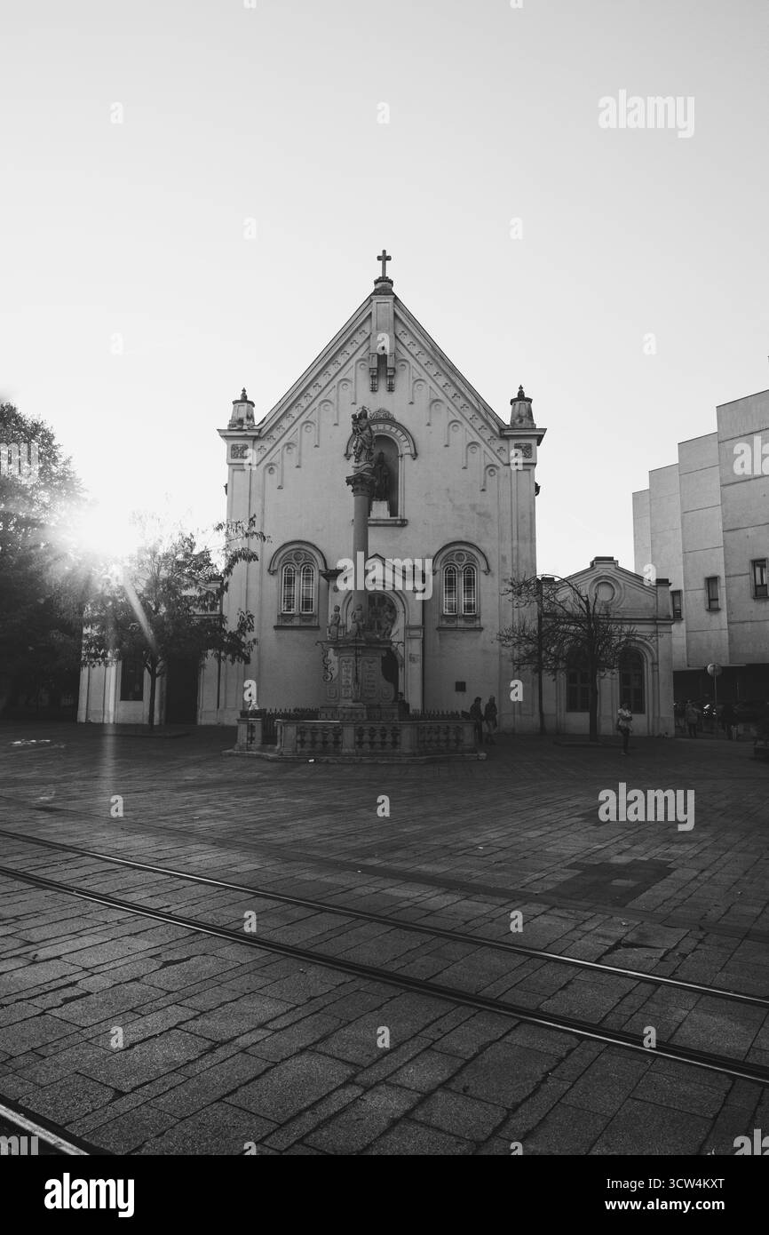 A historic church sits in a peaceful square, bathed in warm sunset ...