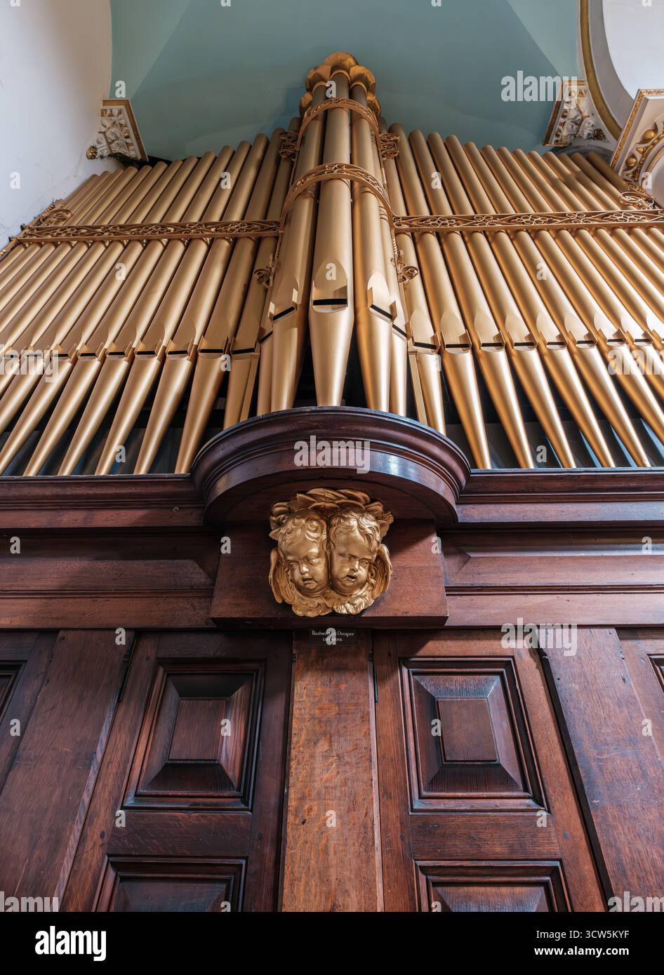 Close-up of ornate pipe organ with gilded cherub decoration inside ...
