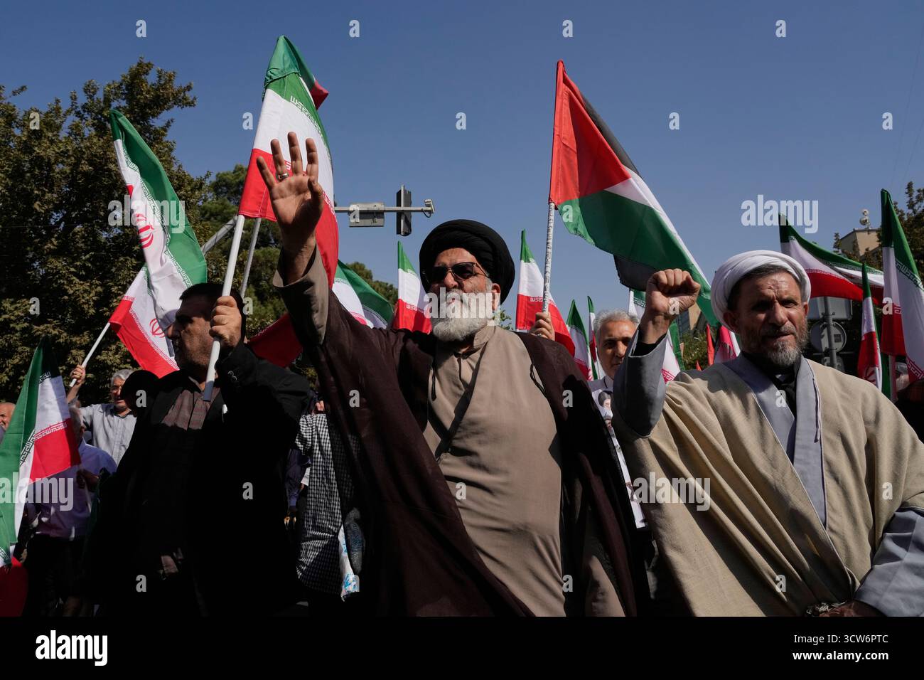 Iranian clerics chant slogans as worshippers hold Iranian and ...