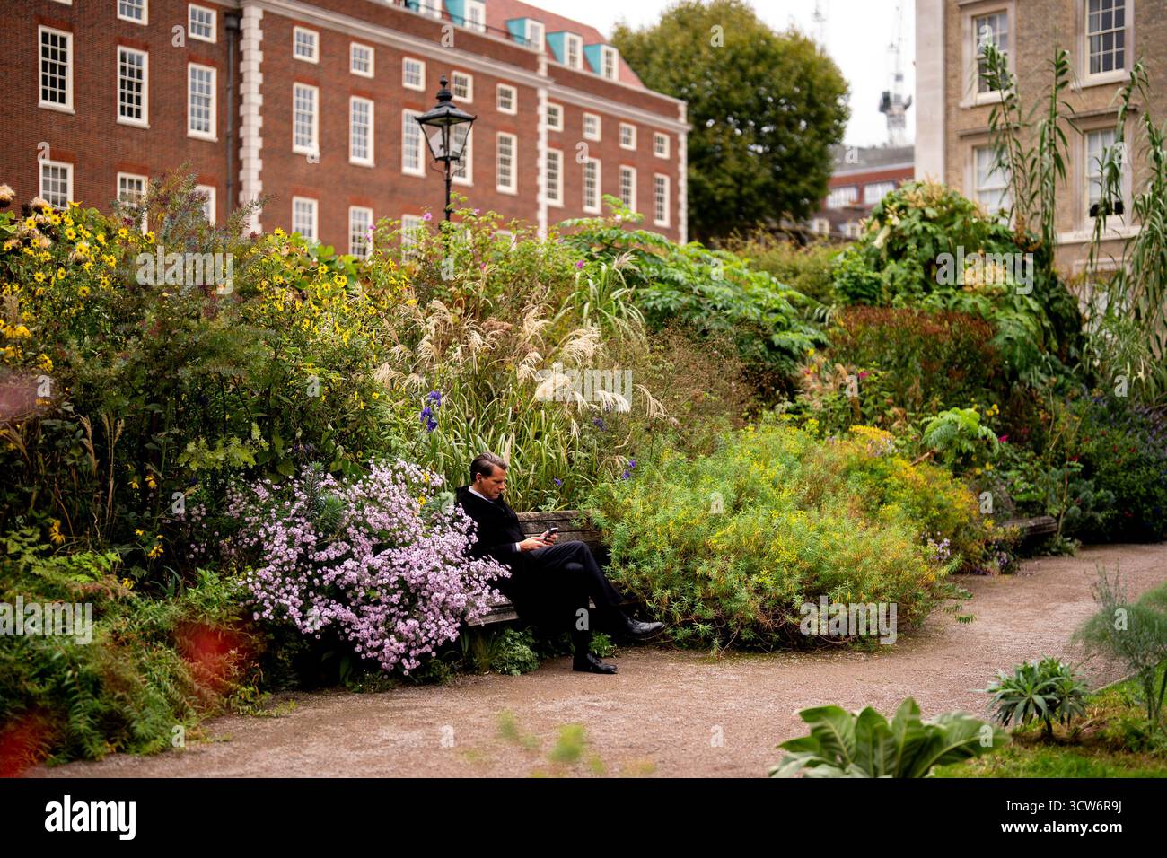 A man on a bench surrounded by autumn colour in Inner Temple Gardens in London. Picture date ...