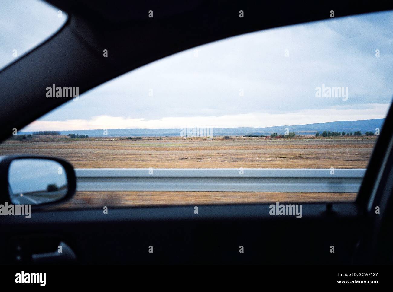 Afternoon drive, viewed through passenger window. Highway rail, yellow ...