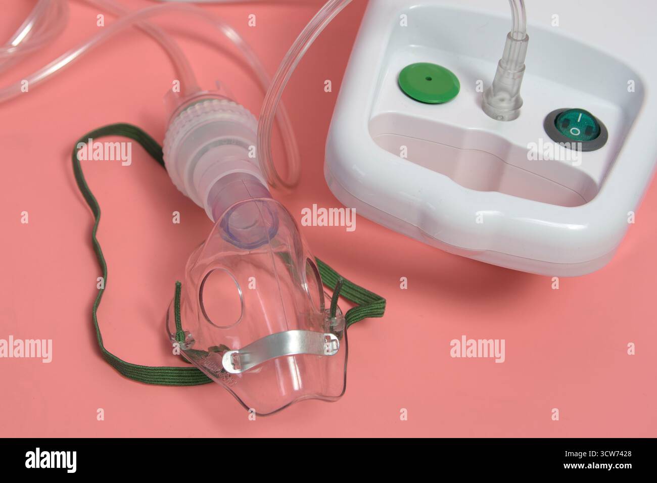 A clear plastic medical mask with a green strap is attached to a tube ...