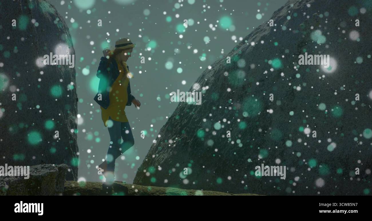 Hiker navigating narrow ledge between boulders on cliff with straw hat ...