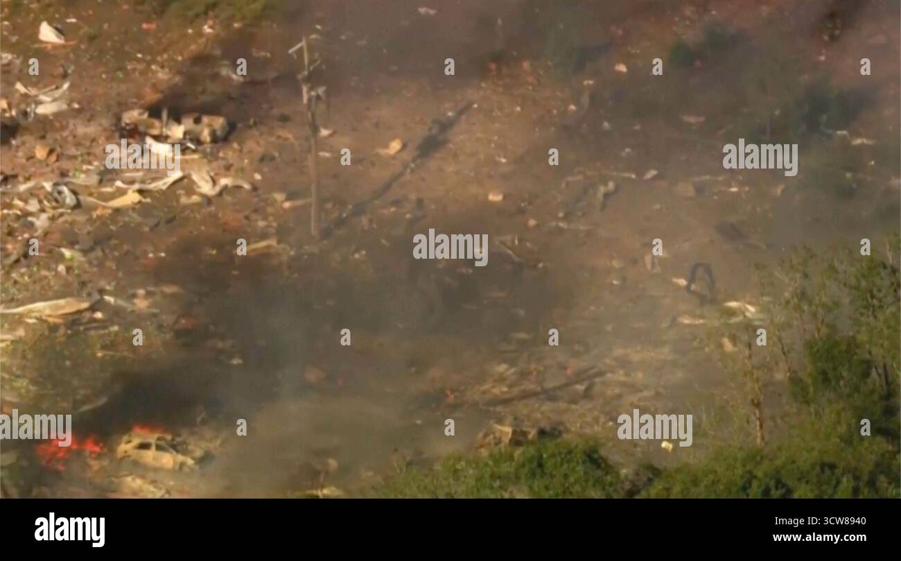 Smoke fills the air as debris covers the ground and vehicles after a ...