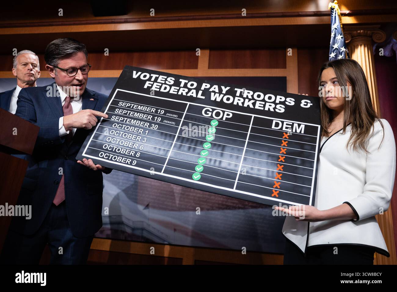 House Speaker Mike Johnson (R-La.) points at a sign comparing ...