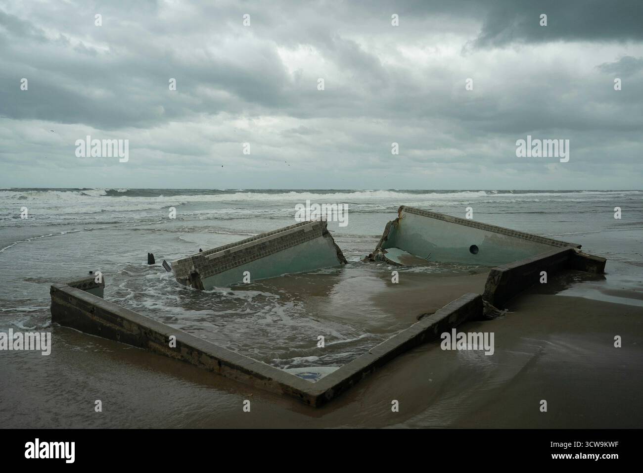 The remains of a swimming pool are seen on the beach as a storm ...