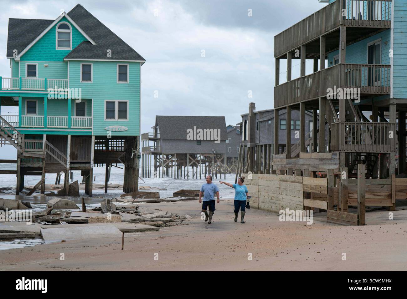 People walk past debris and home at risk of falling into the ocean at ...