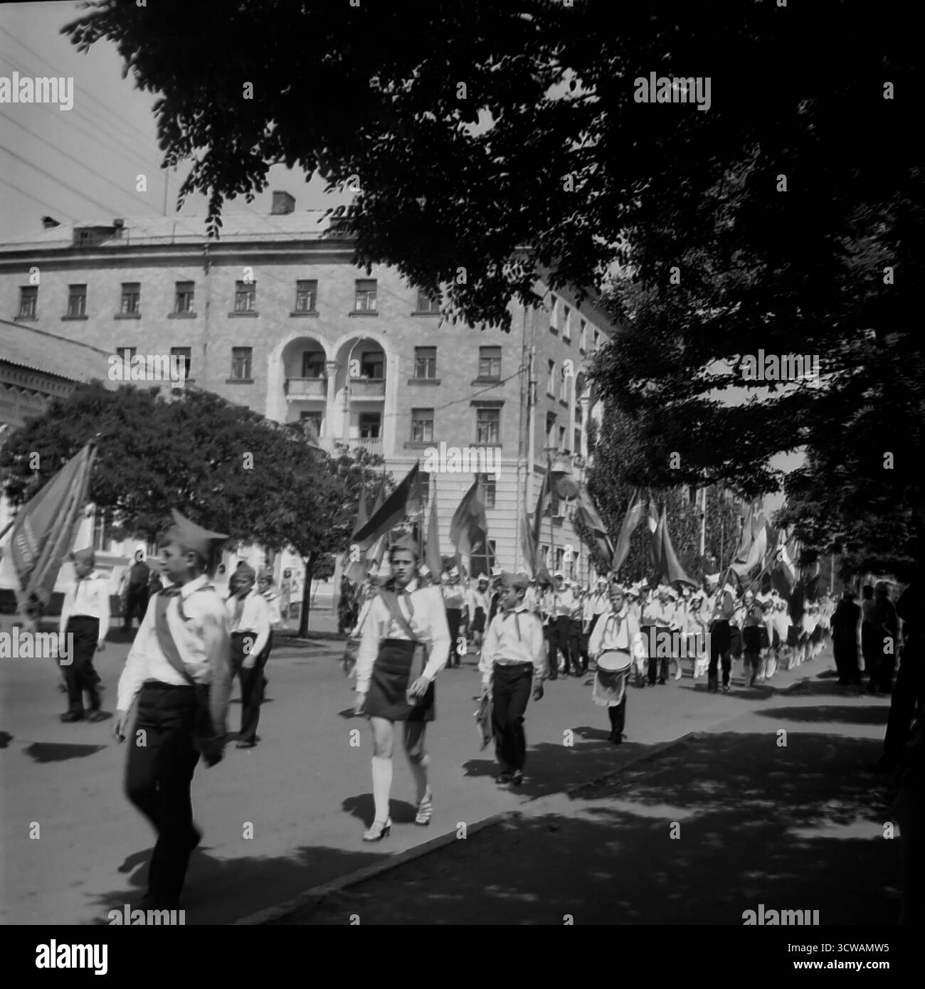 Columns of uniformed Soviet Pioneers march with large red banners ...