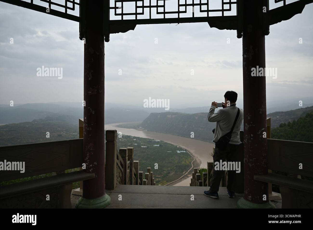 08 October 2025, China, Yan'an: A man photographs the Yellow River in ...