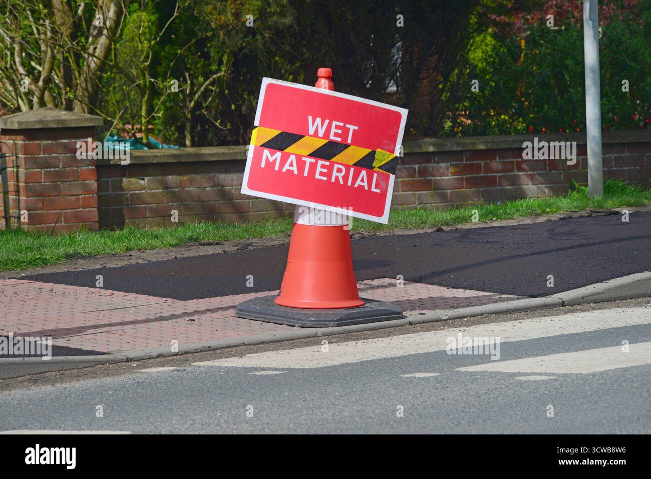 warning sign of wet tarmac on roadside footpath united kingdom Stock ...