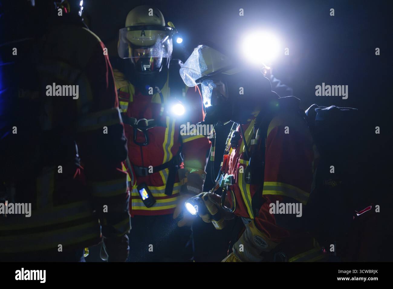Group of firefighters with breathing masks and lights during a night ...