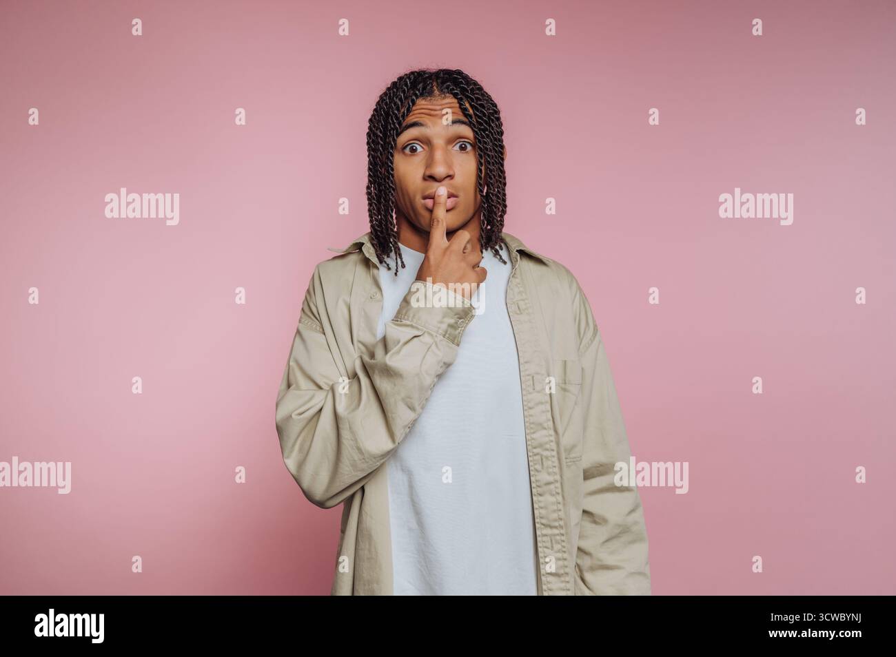 portrait of young man gestures for silence with a finger on his lips ...