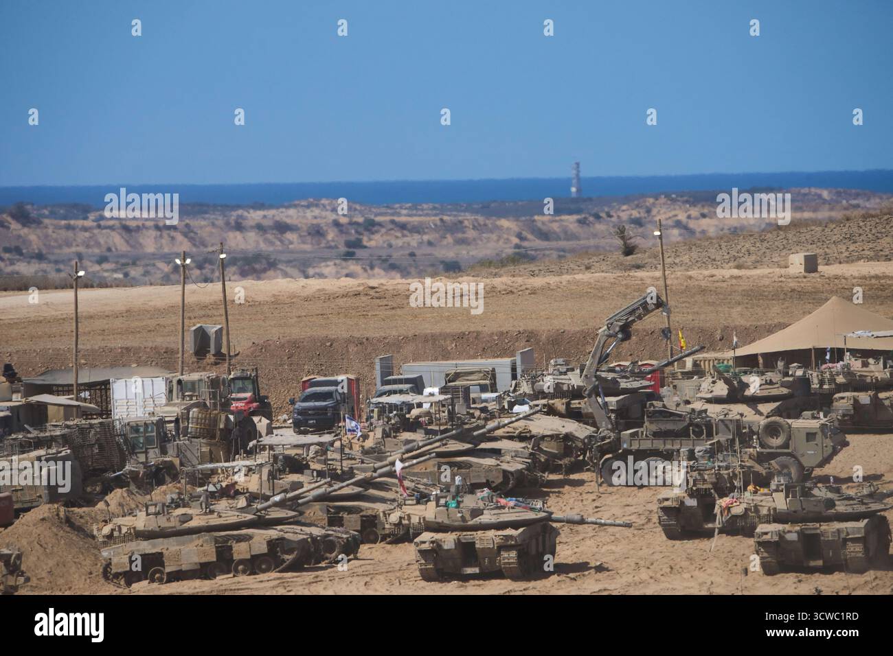 Israeli soldiers work on their tanks at a gathering point on the border ...