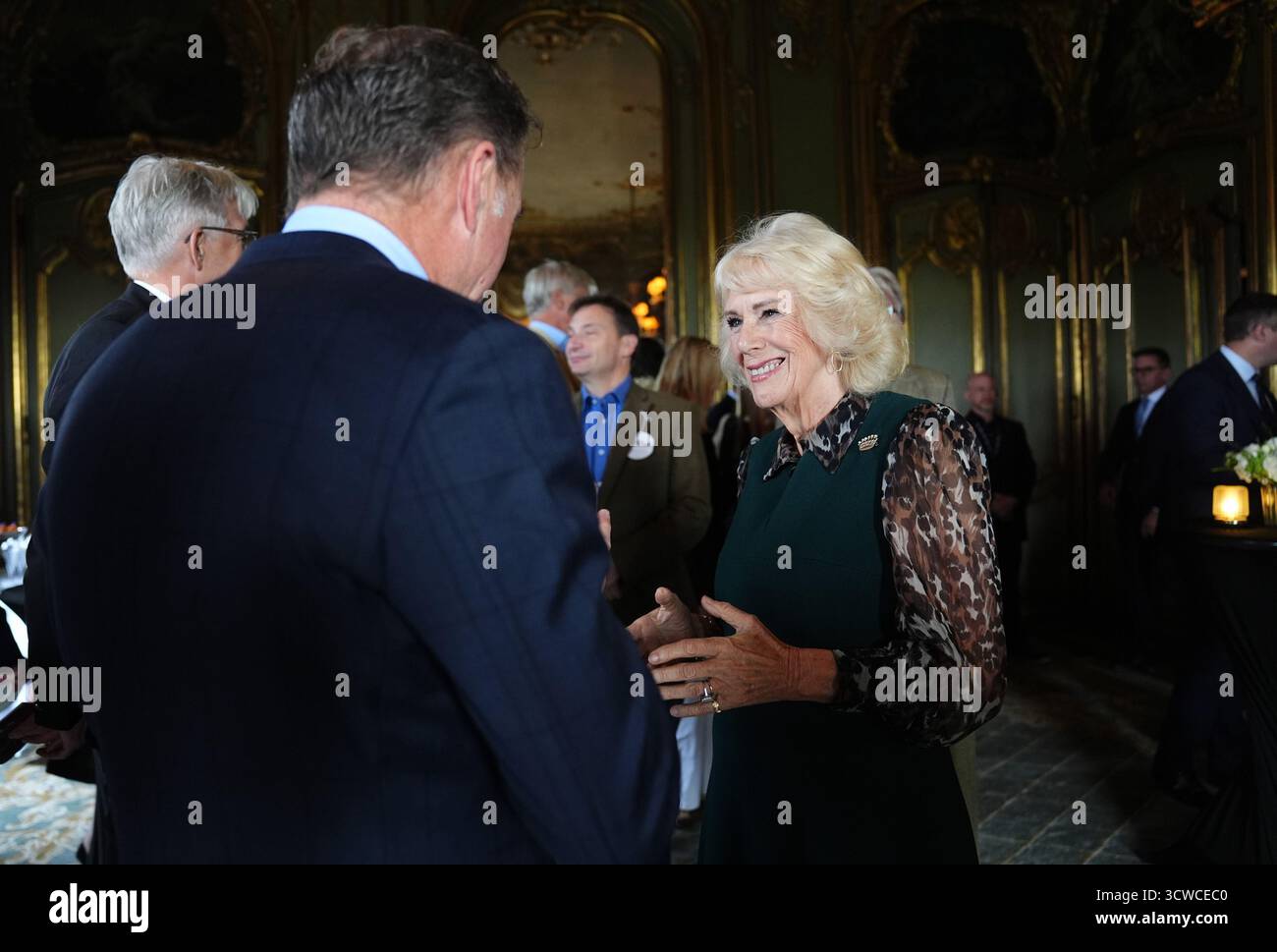 Queen Camilla speaking to guests at a reception in Cliveden House after ...