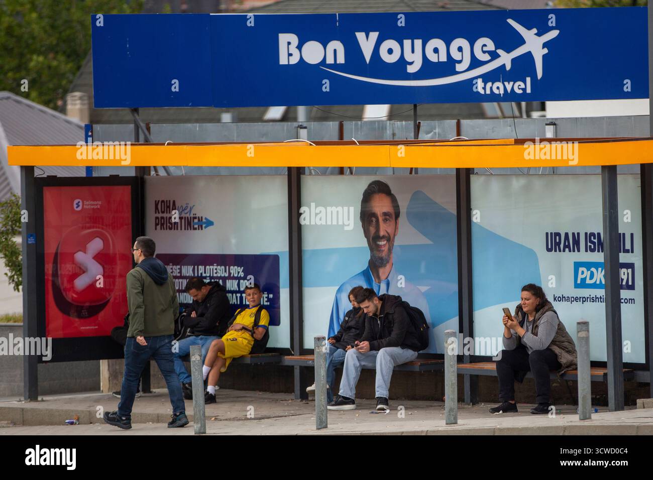 People wait at the bus station decorated with political banner of the ...