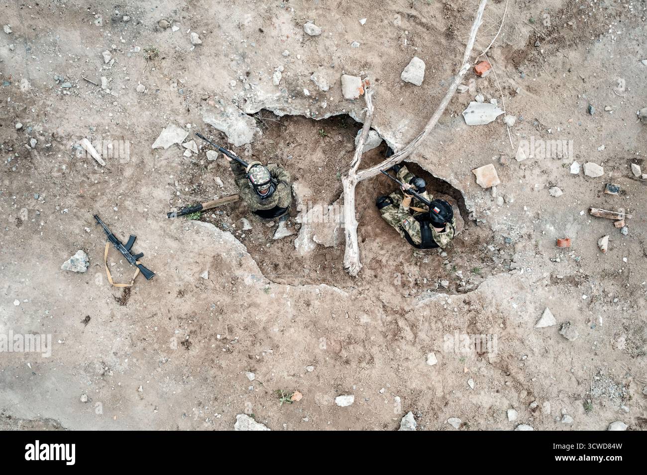 aerial view of two soldiers in military uniforms sitting in trench with ...