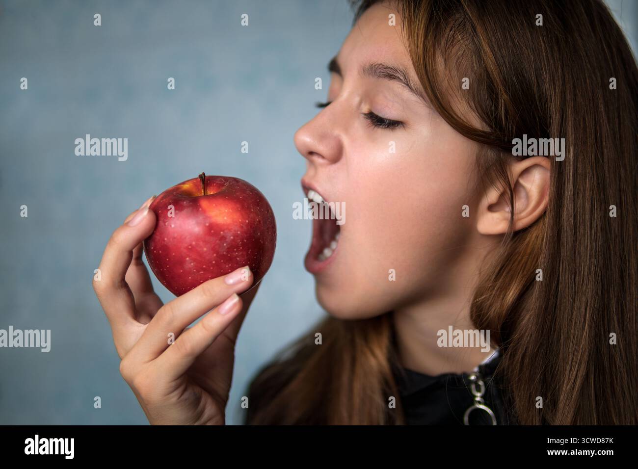 Cute girl looking aside with widely open mouth ready to eat red juicy ...