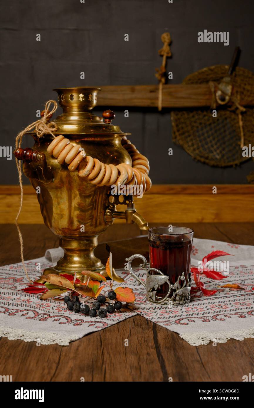 A samovar with buns and a glass of tea in a glass holder on a ...