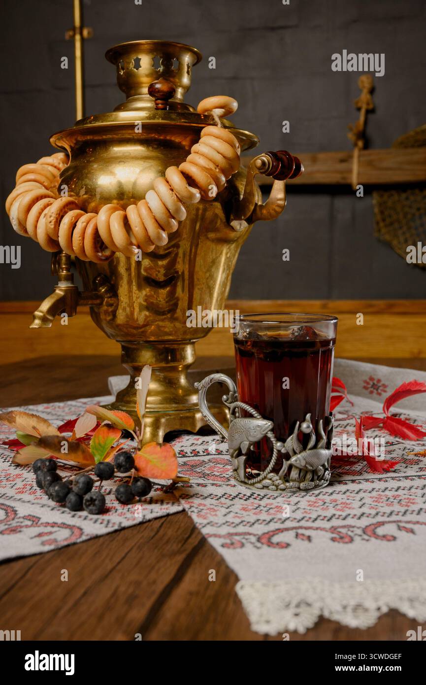 A samovar with buns and a glass of tea in a glass holder on a ...