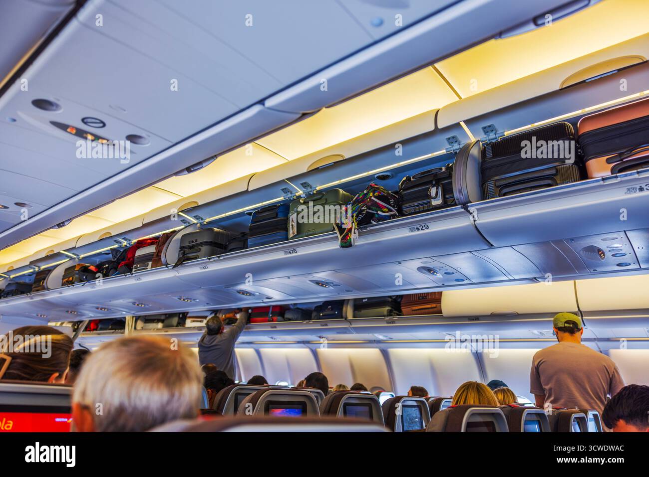 Passengers placing luggage in airplane overhead compartments during ...