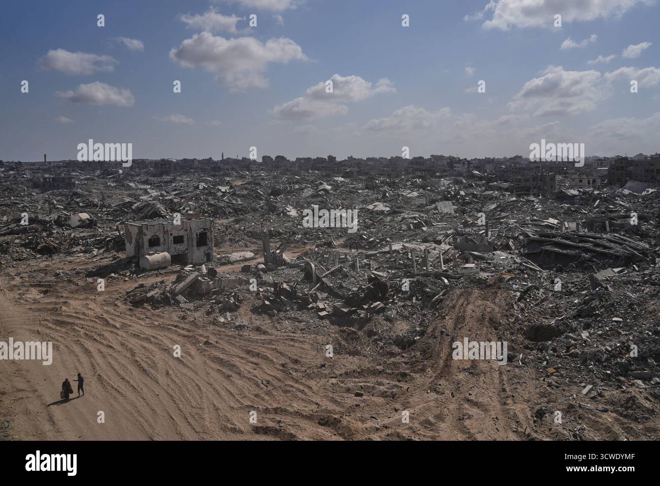 Two displaced Palestinians walk past destroyed buildings in the heavily ...