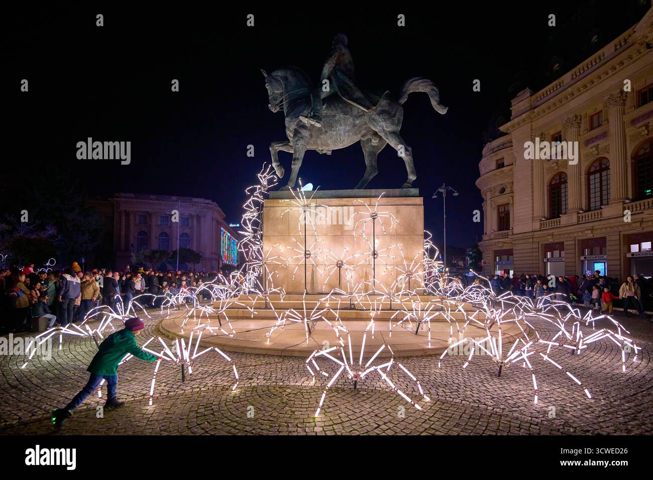 A child touches a light installation depicting spiders, placed around ...
