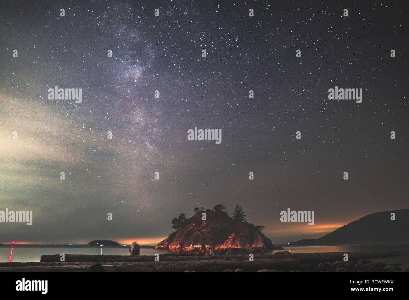 A serene coastal scene at night shows a small island illuminated by ...
